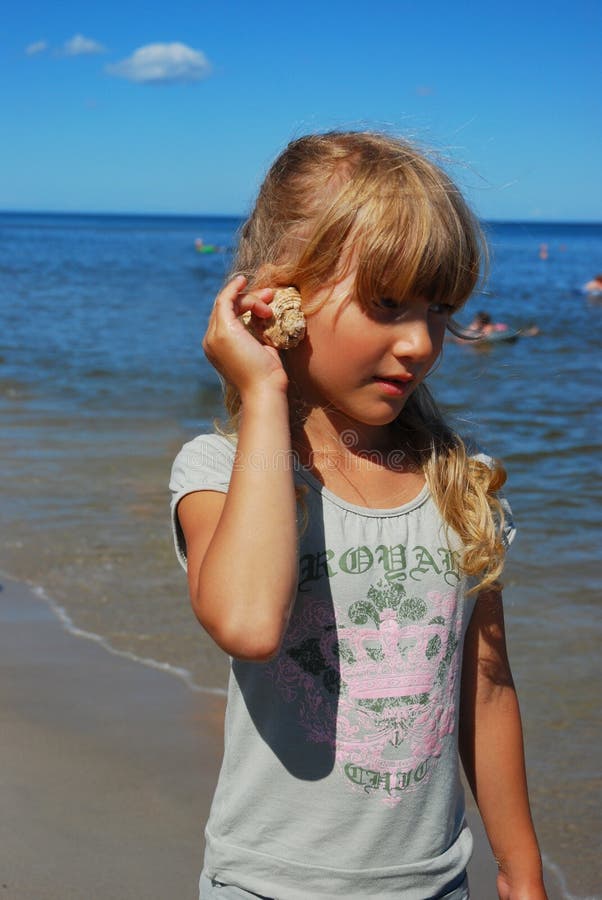 Girl Listening To Sea Shell Stock Photo - Image of amazement ...
