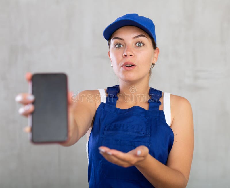 Young Girl in a Blue Construction Overalls Shows the Screen of Modern ...