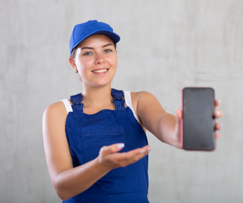 Young Girl in a Blue Construction Overalls Shows the Screen of Modern ...