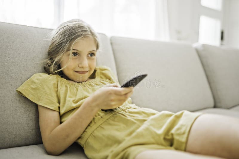 Young Girl Child Sitting on the Couch Using a Remote Control Stock ...