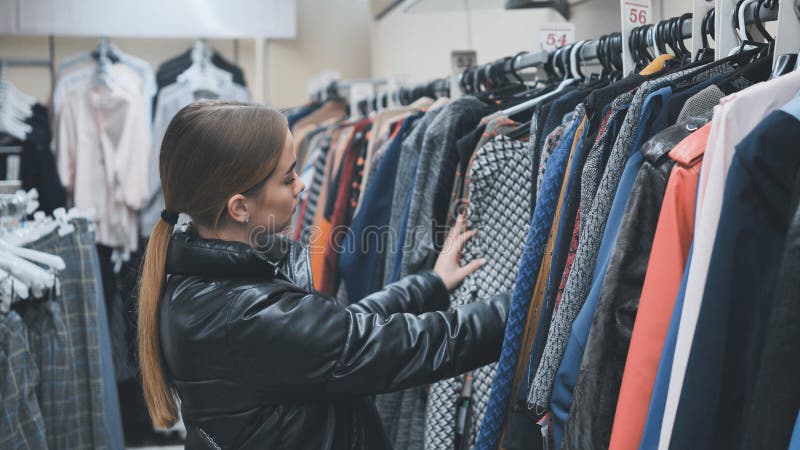 A Young Girl Choosing and Looking at Clothes in the Store. Stock Image ...