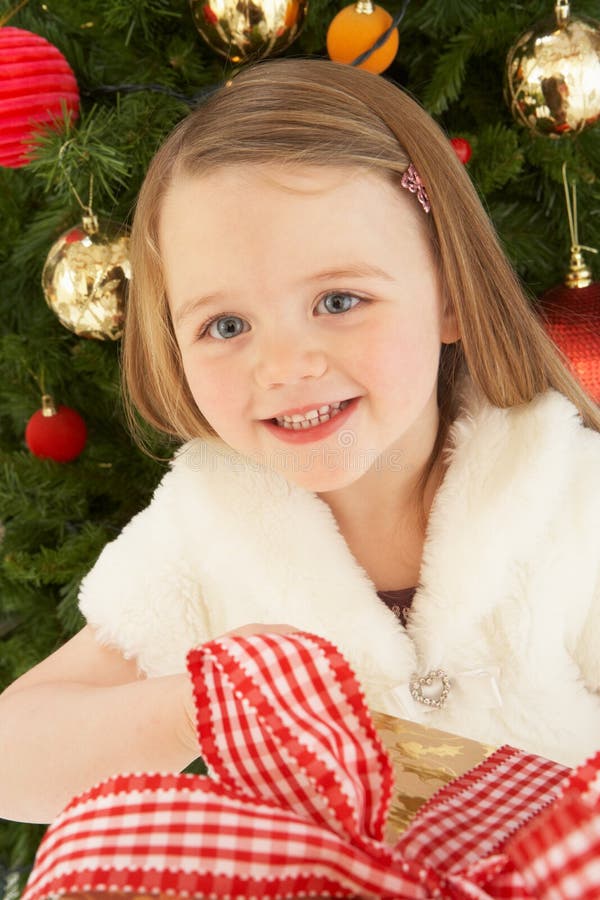 Young Girl Holding Gift in Front of Christmas Tree Stock Image - Image ...