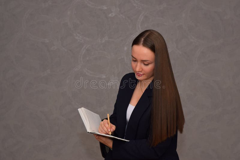 A Young Girl with a Notebook and Pen is Standing Against the Wall ...