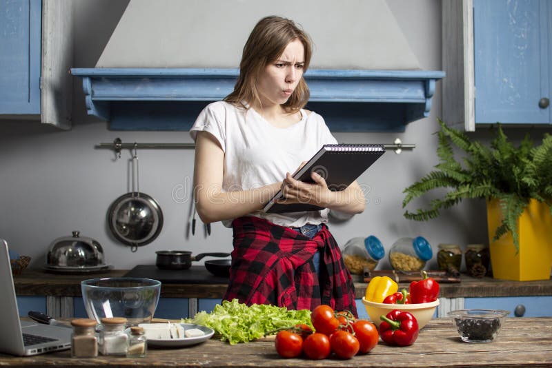 Young Girl Prepares A Vegetarian Salad In The Kitchen And Looks Into A