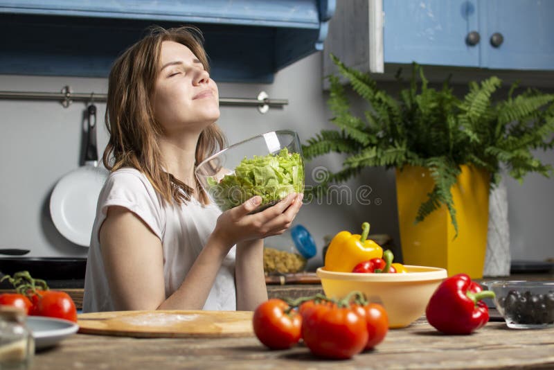 Young Girl Prepares A Vegetarian Salad In The Kitchen She Smells The
