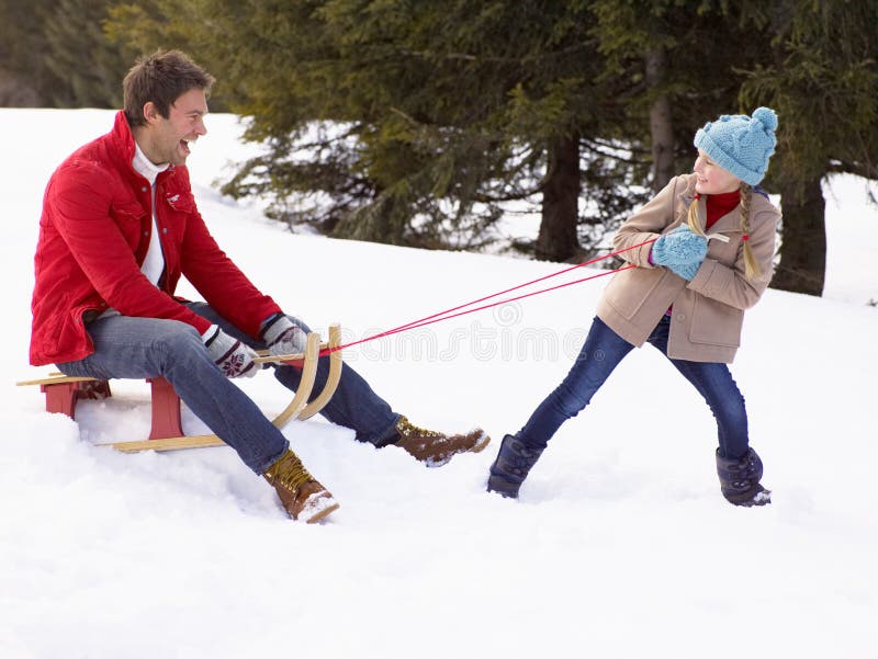 Young Girl Pulling Father through Snow on Sled Stock Photo - Image of ...