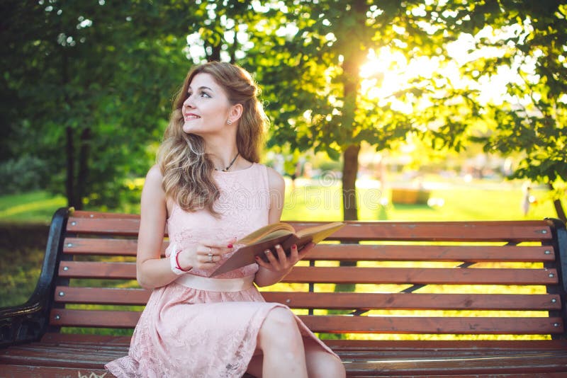 A Young Girl Reading a Book Sitting on a Bench at Sunset Stock Image ...