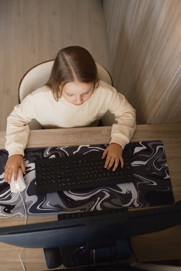 Young Girl Using Computer at Wooden Desk for Learning or Web Browsing ...