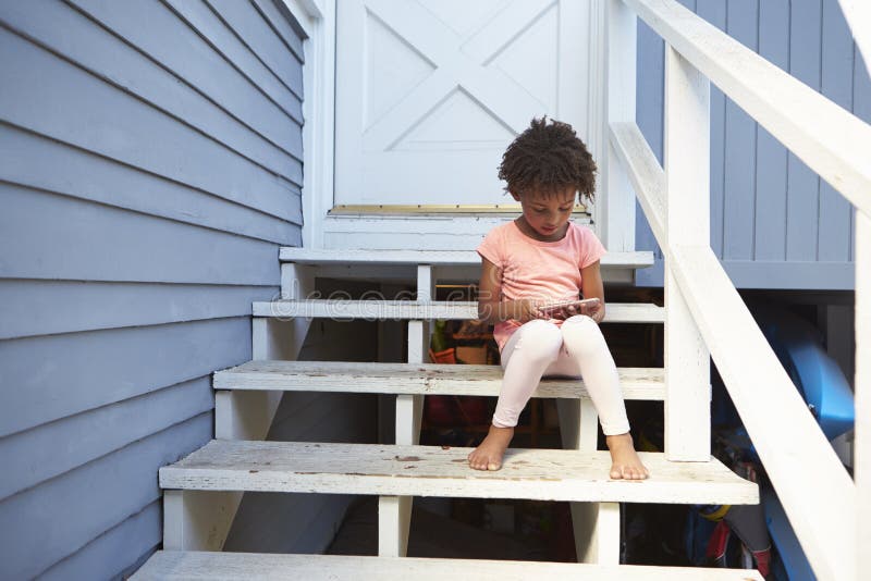 Young Girl Sits on Outdoor Steps Playing with Mobile Phone Stock Image ...