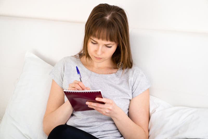 Woman Sitting on the Bed and Writing in a Notebook Stock Image - Image ...