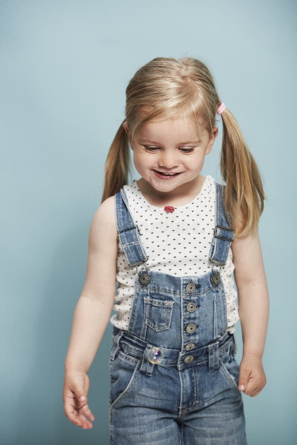 Young Girl Standing Against Blue Background, Looking Down Stock Image ...