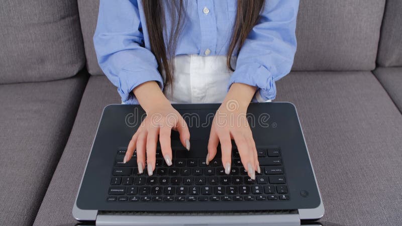 Young Girl Typing Text on a Laptop Keyboard while Sitting on a Couch at ...