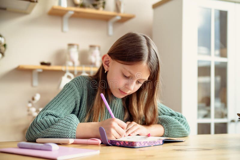 A Young Girl Writes in Her Journal at the Table during the Day Inside ...