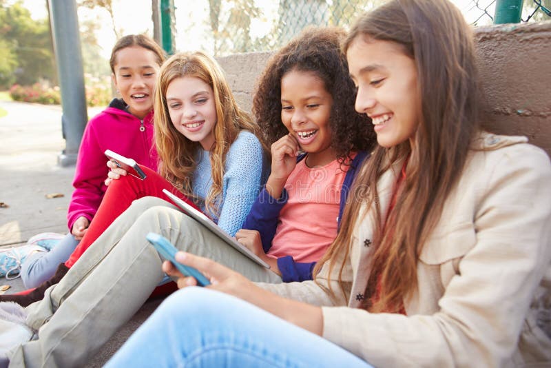 Young Girls Using Digital Tablets and Mobile Phones in Park Stock Photo ...
