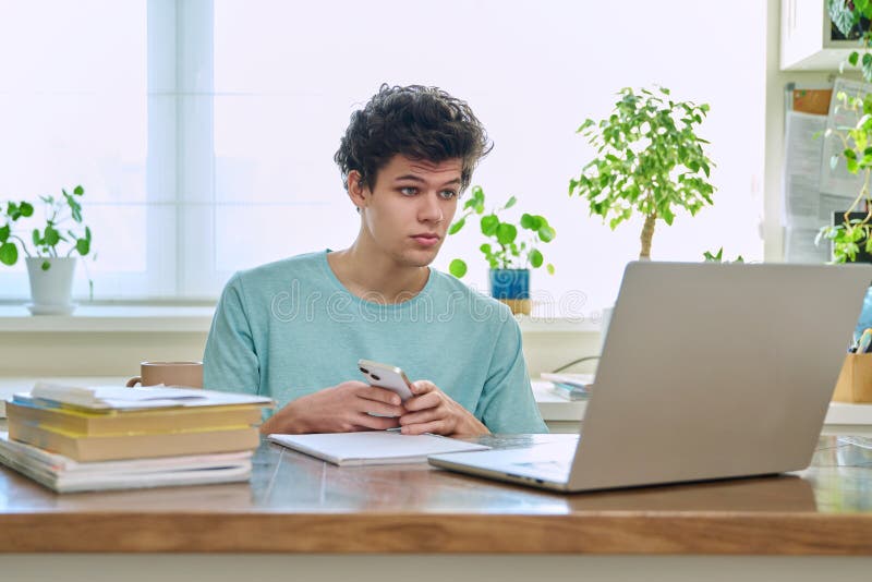 Young Guy College Student Sitting at Home at Desk Using Smartphone ...