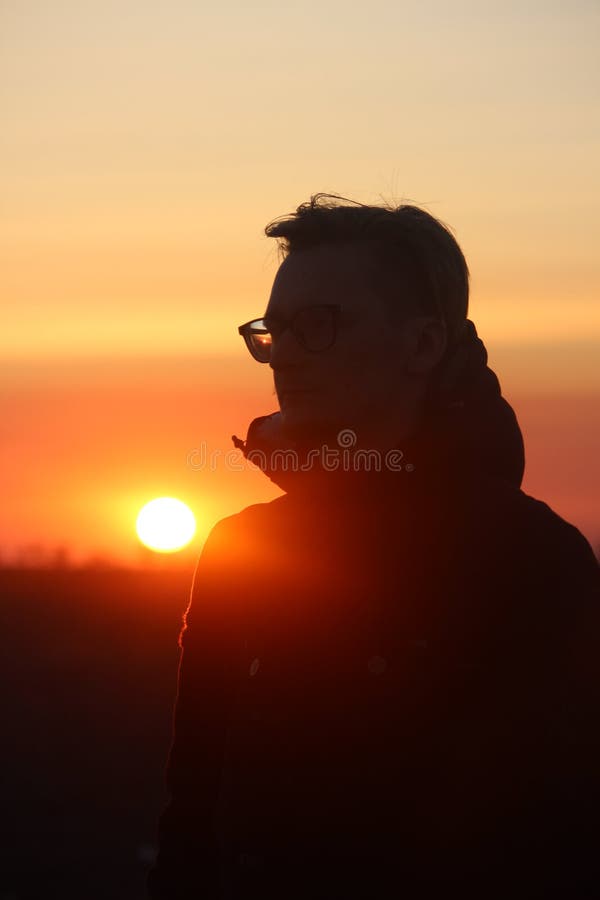 A Young Guy with Glasses Stands Against the Backdrop of Sunset Stock ...