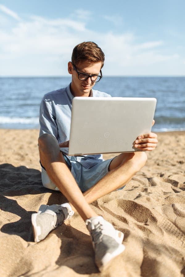 Young Guy with Glasses, Working on His Laptop on the Beach, Work on ...