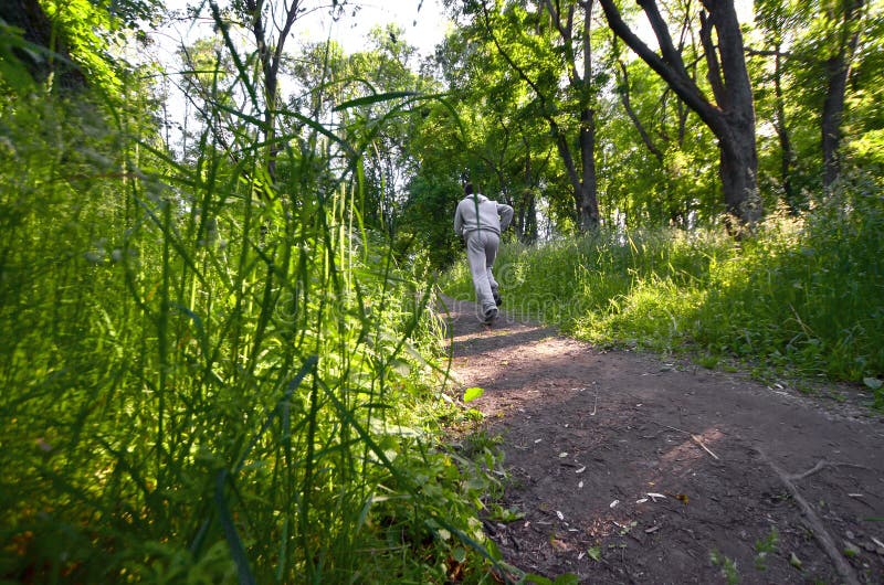 A Young Guy in a Gray Sports Suit Runs Along the Path among the Stock ...