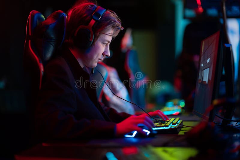 A Young Guy in a Headset Plays Shooting Games in the Computer Room ...