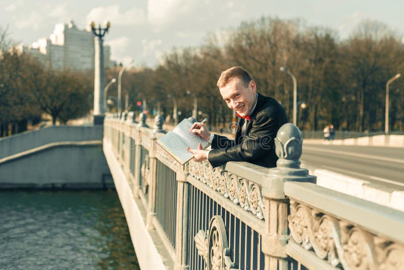 Young Guy Smiling on the Bridge. Man Holding a Notebook. Stock Photo ...