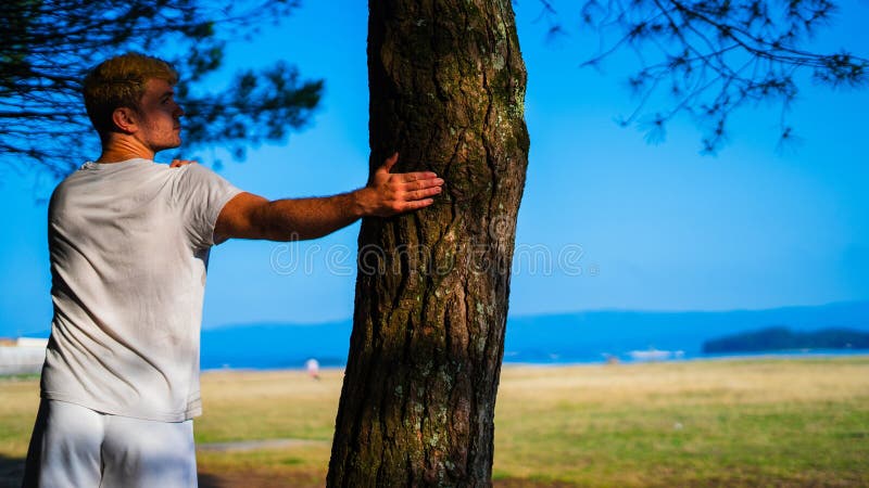 Young Guy Stretching His Arm with a Trees Help Stock Image - Image of ...