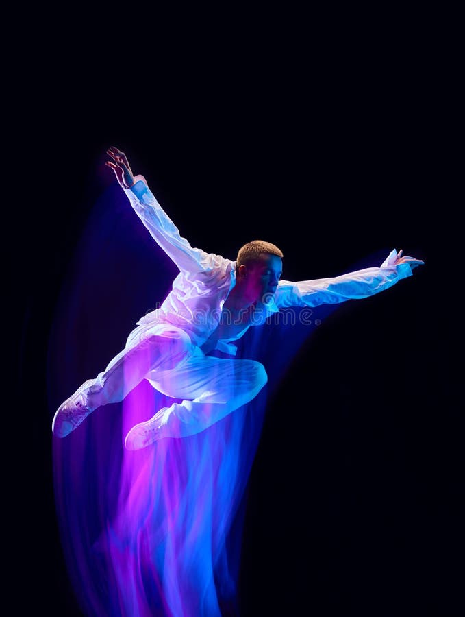 Young Guy in Stylish White Clothes in Motion, Jumping Against Black ...
