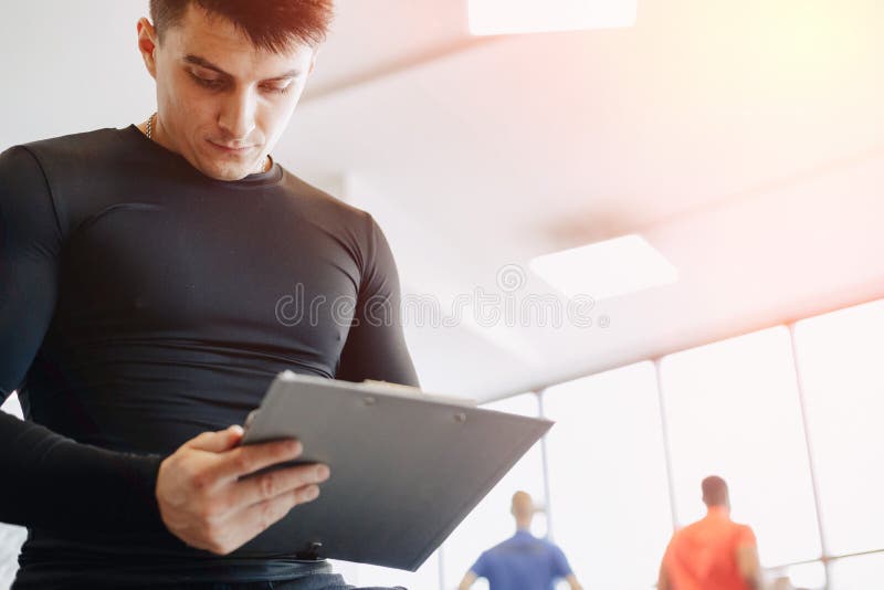 Young Guy Trainer Takes Notes in the Gym. Personal Trainer for Sports ...