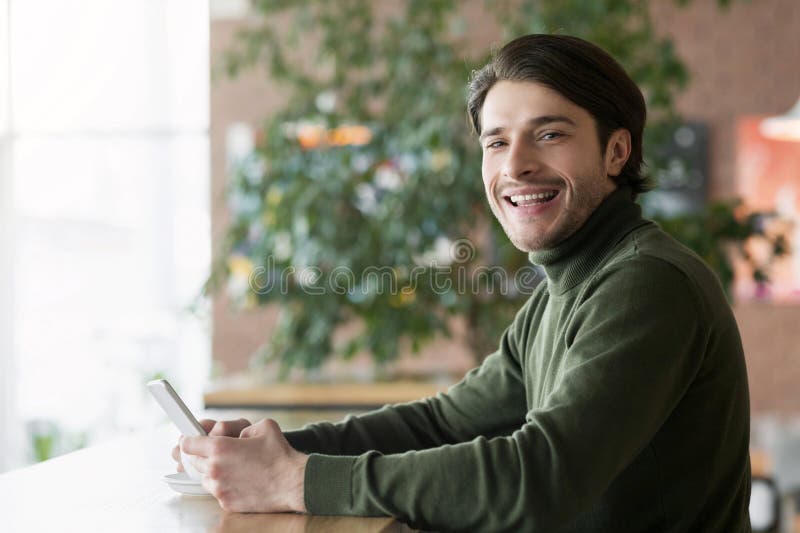 Young Guy Using Mobile Phone at Cafe, Smiling at Camera Stock Photo ...
