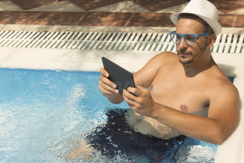 Young Guy Using Tablet Device while Relaxing in the Swimming Pool Stock ...