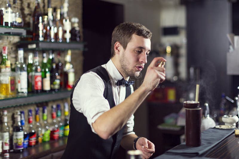 A Young Guy Working As a Bartender Behind a Bar is Preparing Drinks ...