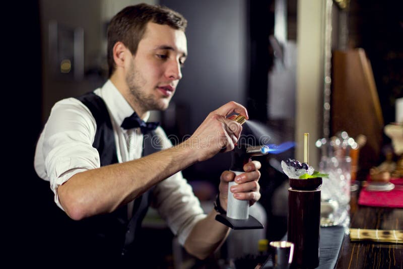 A Young Guy Working As a Bartender Behind a Bar is Preparing Drinks ...