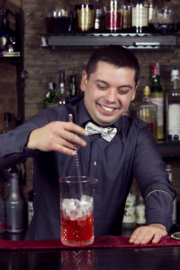 A Young Guy Working As a Bartender Behind a Bar is Preparing Drinks ...