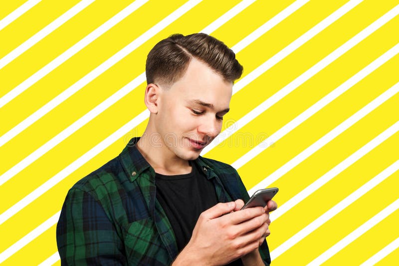 Young Guy Writes a Message on the Mobile Phone and Smiles Stock Photo ...