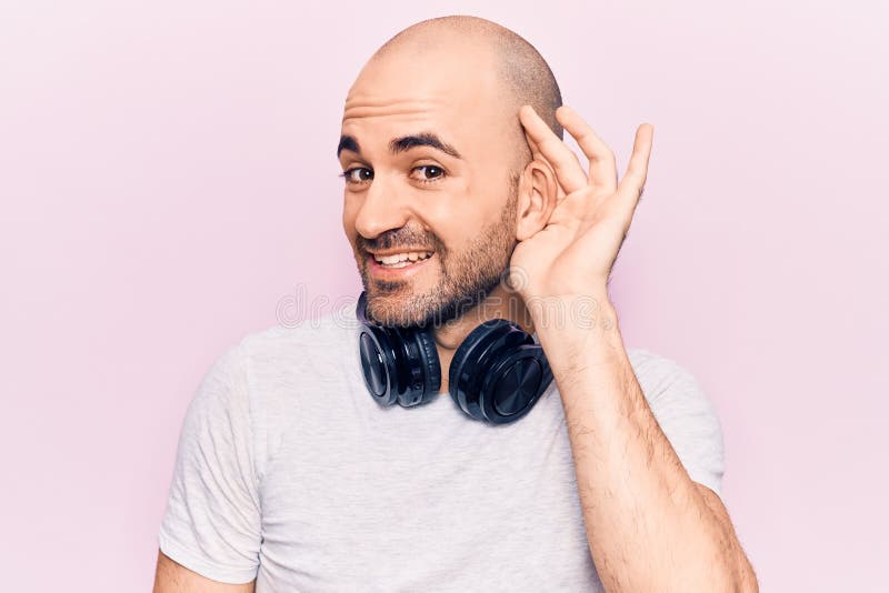 Young Handsome Bald Man Listening To Music Using Headphones Smiling