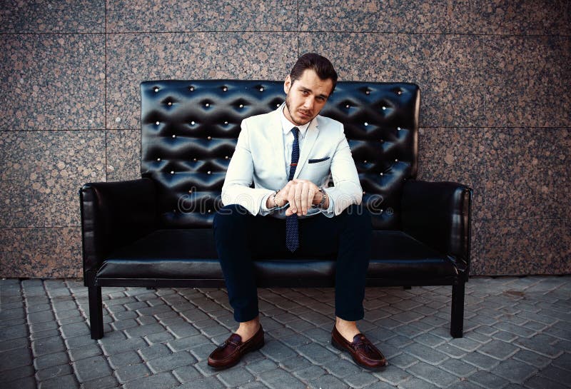 Young Handsome Bearded Stylish Man Sitting On Comfortable Leather Sofa
