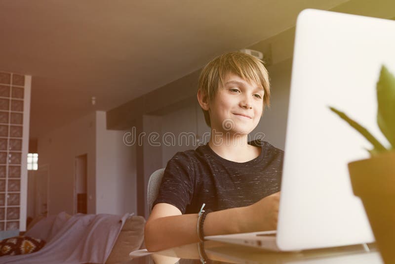 Young Handsome Boy Using Laptop Computer while Sitting at the Table in ...