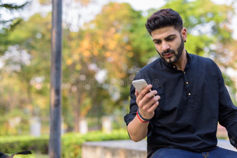 Young Handsome Indian Man Using Mobile Phone while Sitting on Co Stock ...
