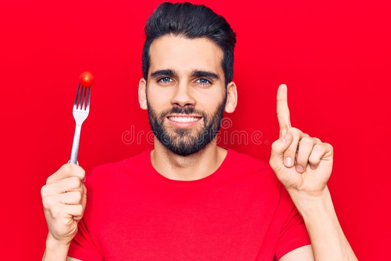 Young Handsome Man with Beard Holding Fork with Tomato Smiling with an ...