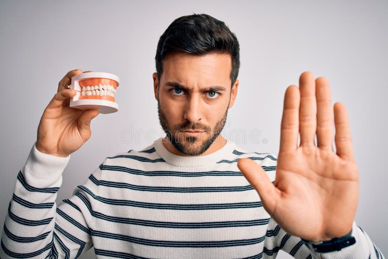 Young Handsome Man with Beard Holding Plastic Denture Teeth Over White ...