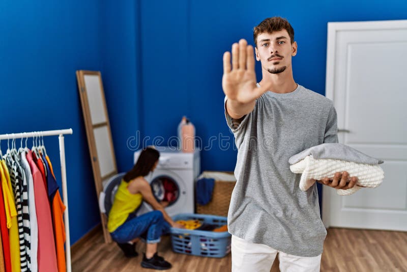 Young Handsome Man Holding Folded Laundry with Open Hand Doing Stop ...