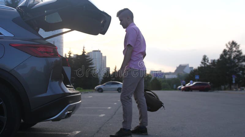 Young Handsome Man Opens Trunk Put Backpack and Close it. Automatic ...