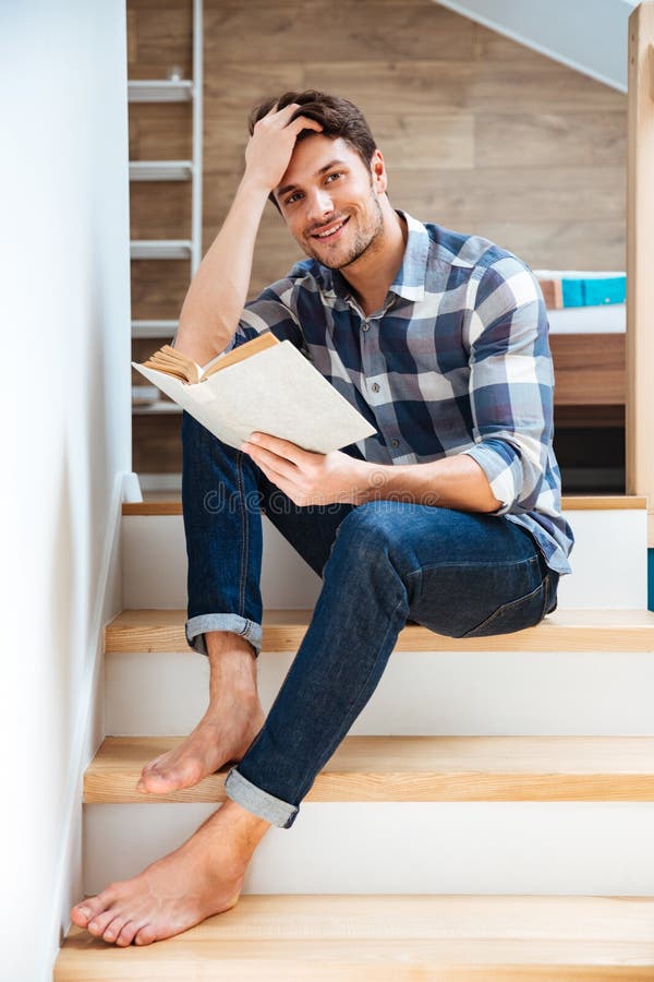 Young Handsome Man Reading Book While Sitting On The Stairs Stock Image