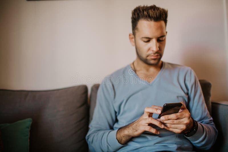 Young Handsome Man Sitting at Home on Sofa and Using Mobile Phone. Men ...