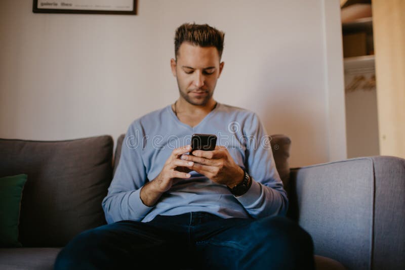 Young Handsome Man Sitting at Home on Sofa and Using Mobile Phone. Men ...
