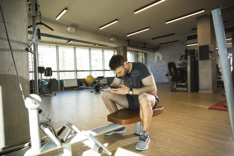 Young Handsome Man Using Phone while Having Exercise Break in Gym Stock ...