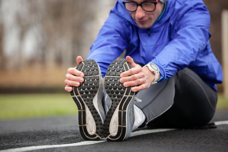 Shot of a Young Handsome Professional Runner Stretching His Feet Stock ...