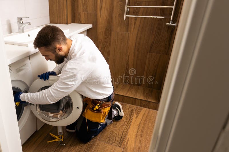 The Young Handsome Repairman in Worker is Fixing the Washing Machine in ...