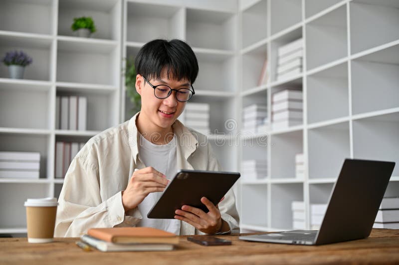Young Happy College Student with Glasses Using Tablet in the Study ...
