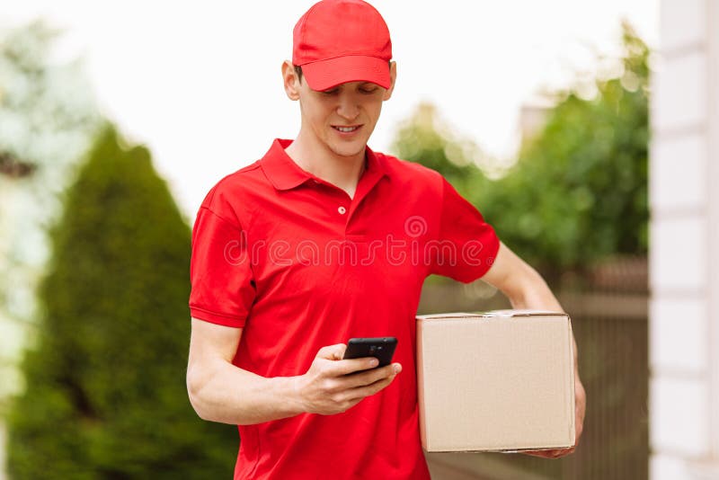 Courier with a Cardboard Box, Using a Mobile Phone. Home Delivery Stock ...