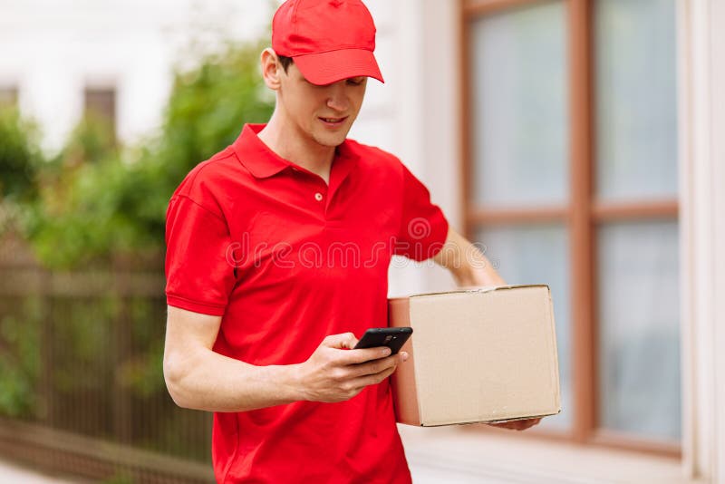 Courier with a Cardboard Box, Using a Mobile Phone. Home Delivery Stock ...
